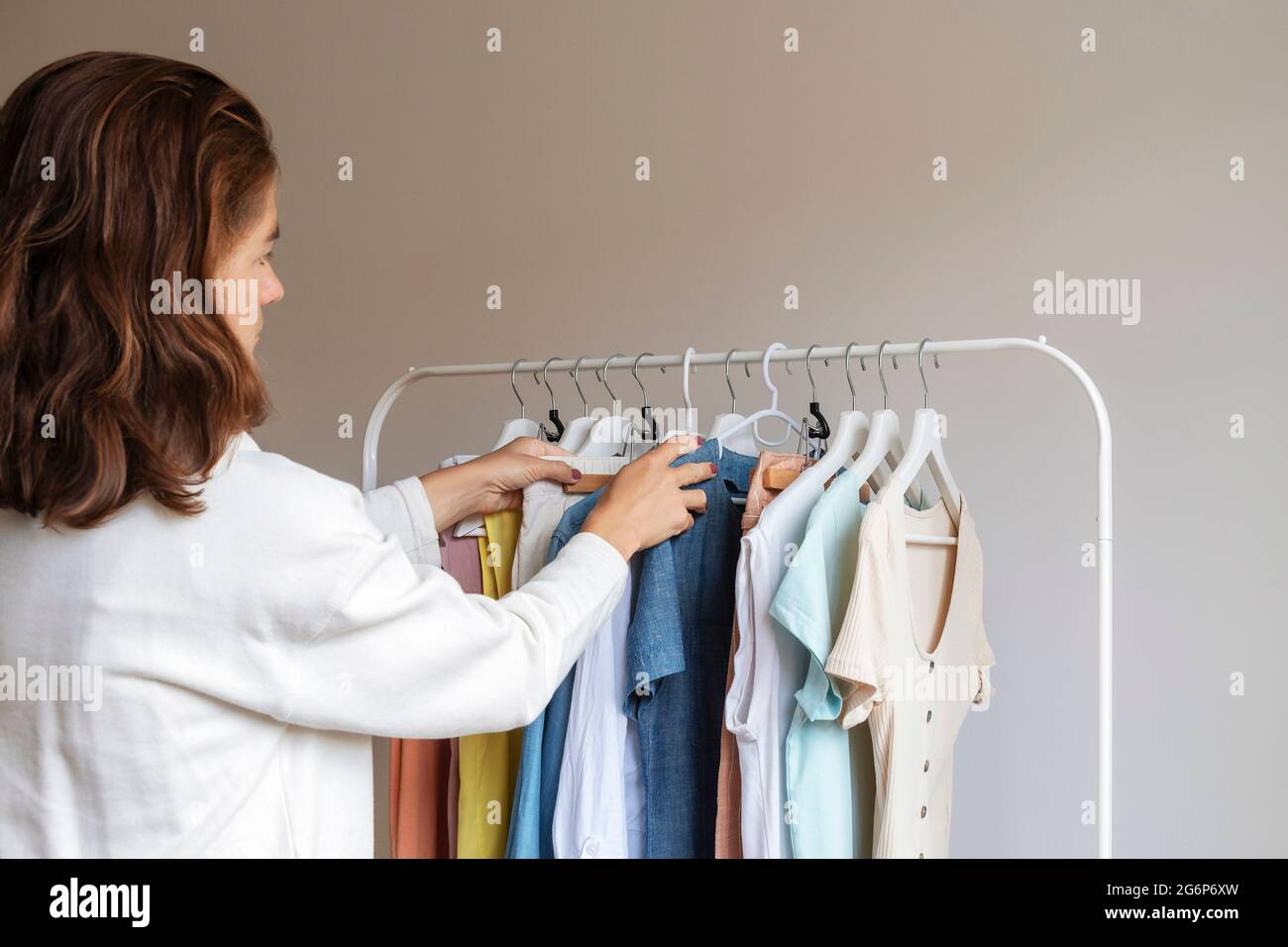 Woman standing in front of hanger rack and choose outfit dressing ...