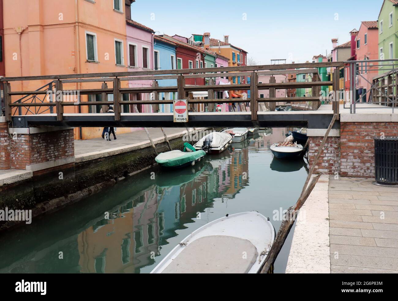 Small wooden bridge over Venice canal with boats underneath and ...