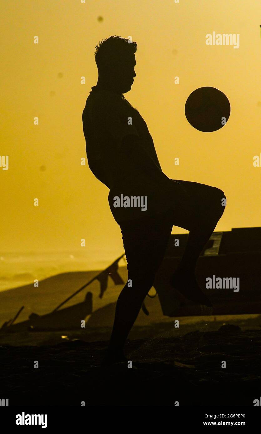 A man plays soccer at San Marcelino beach during sunset. (Photo by ...