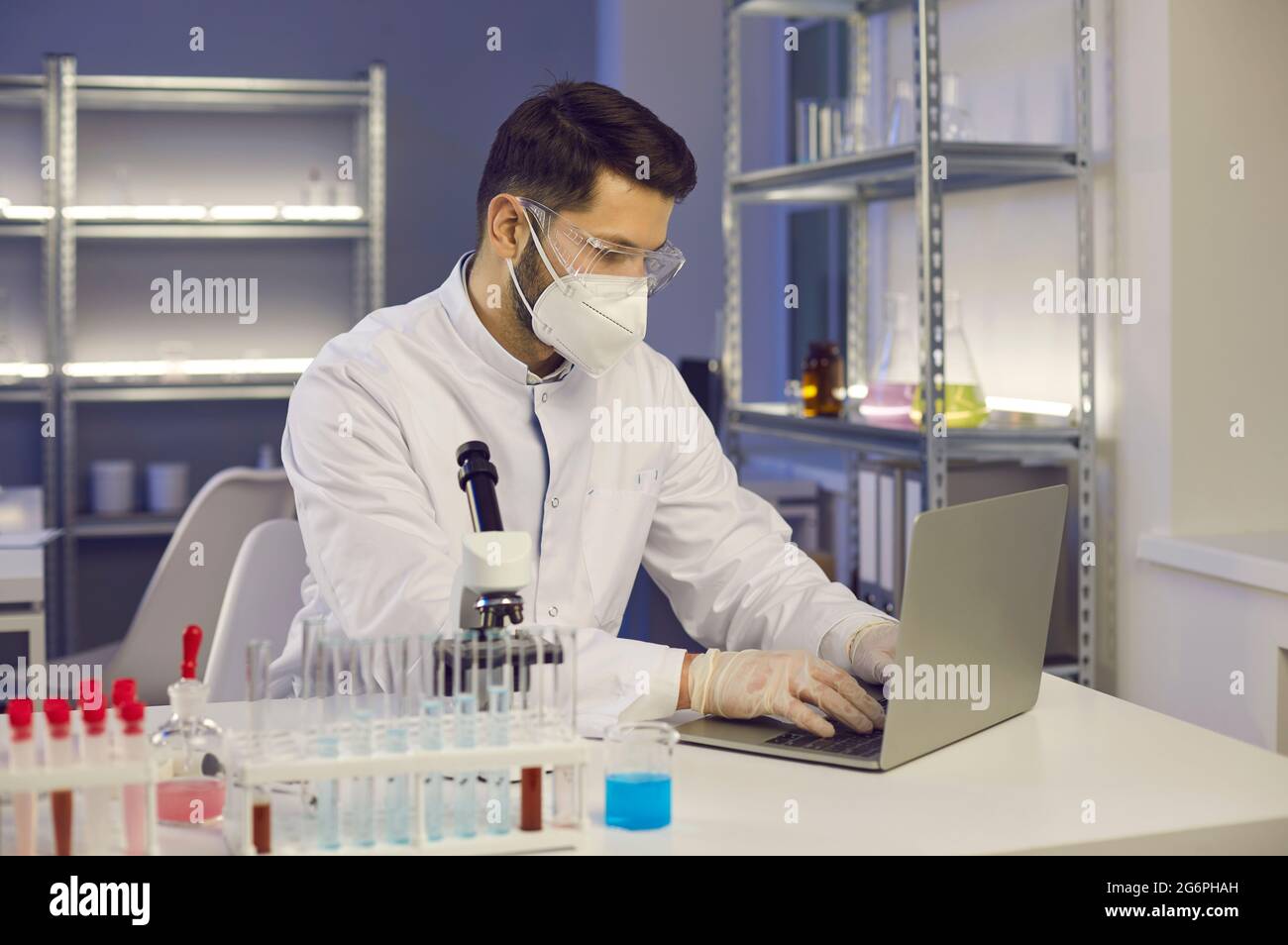 Medical scientist working on a laptop while doing research in a science ...