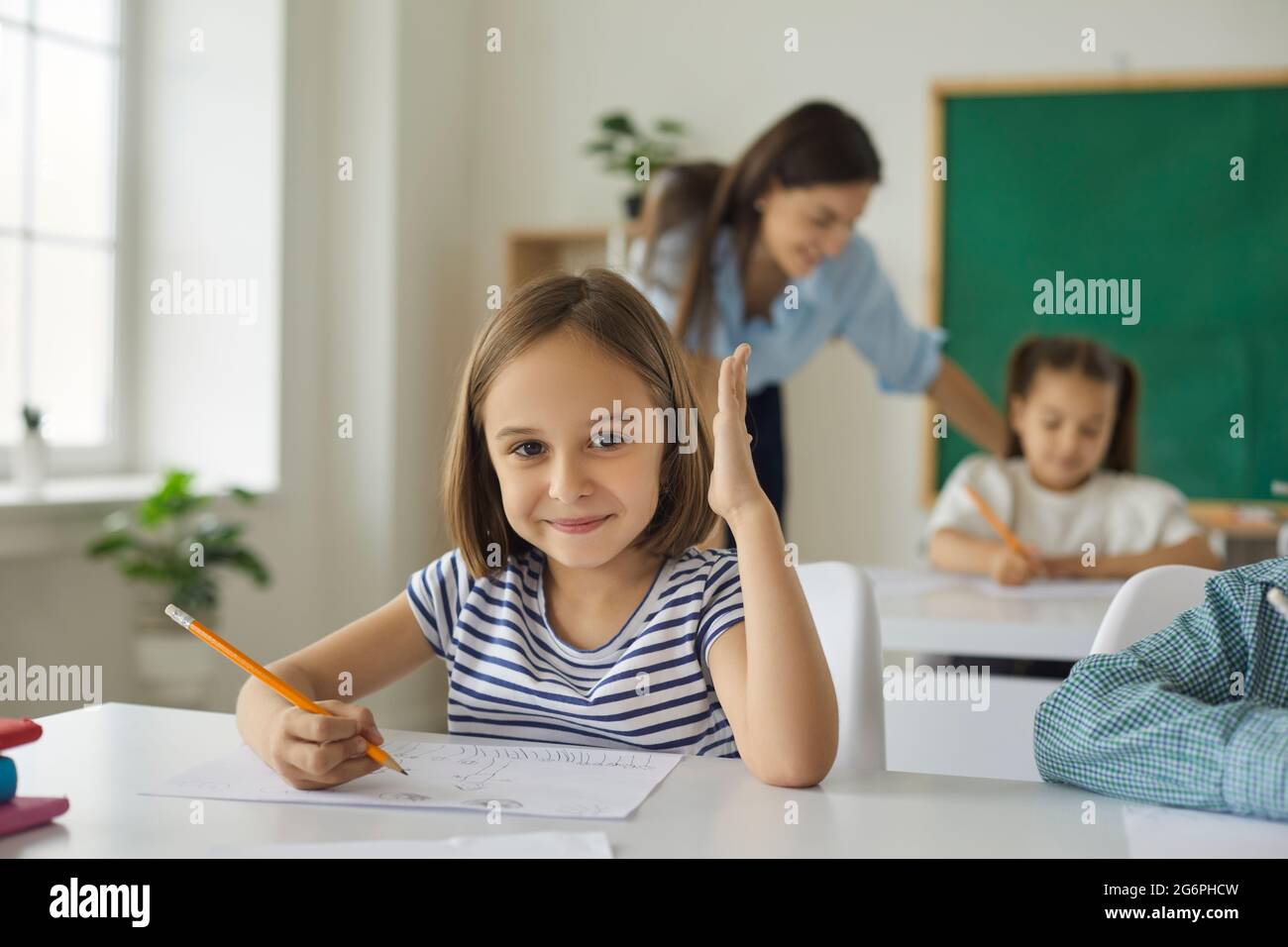 Portrait intelligent primary school girl student raising hand smiling ...