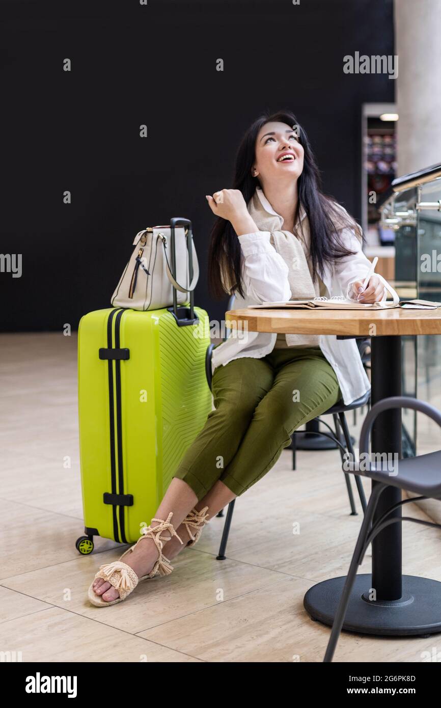 Smiling woman writing making notes in diary sitting at table in ...