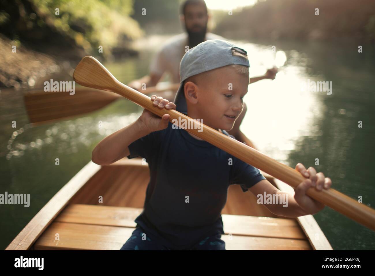 Boy learning to paddle canoe on a lake Stock Photo - Alamy