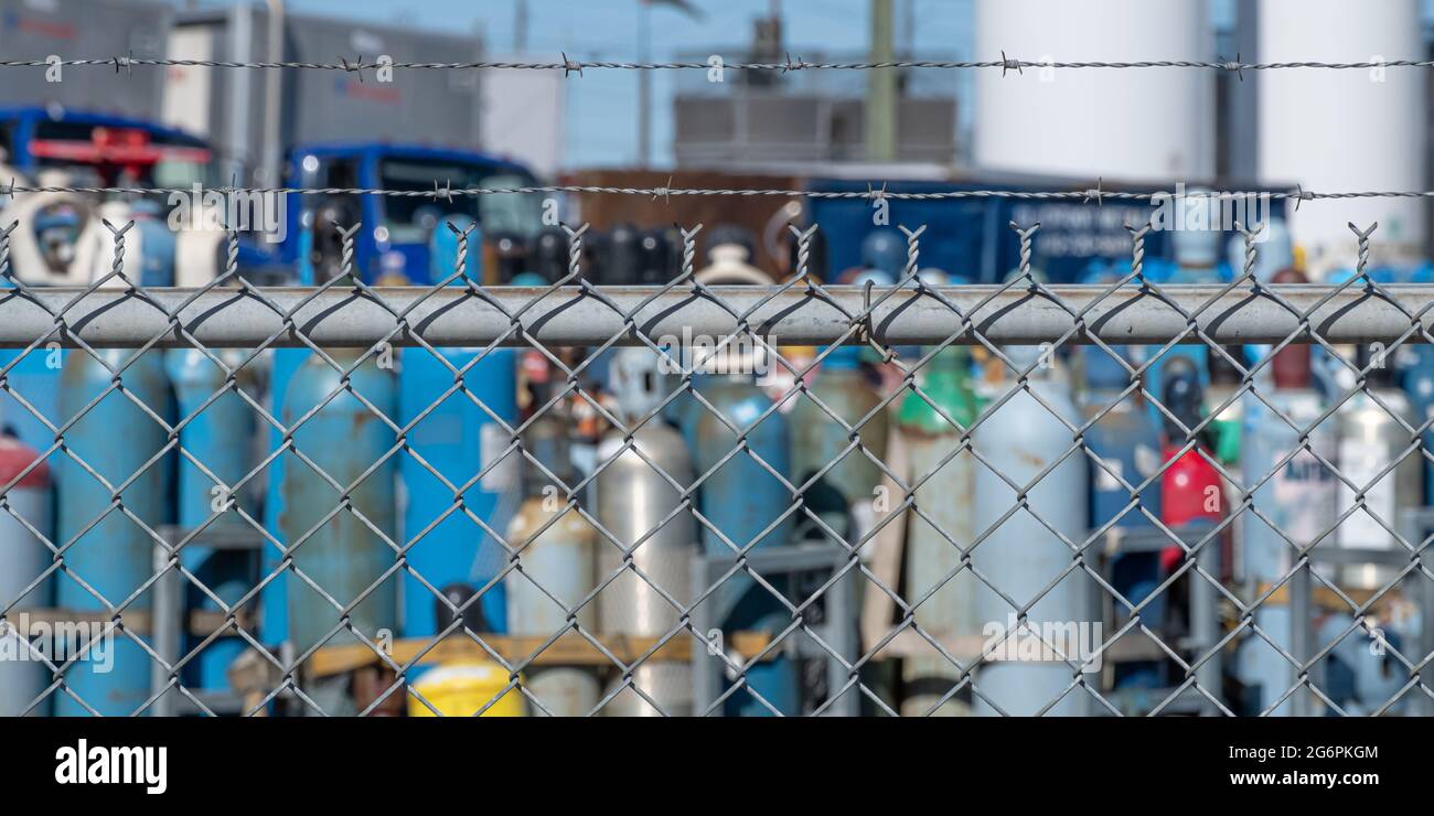 Gas cylinders stored behind wire mesh fence in factory Stock Photo - Alamy