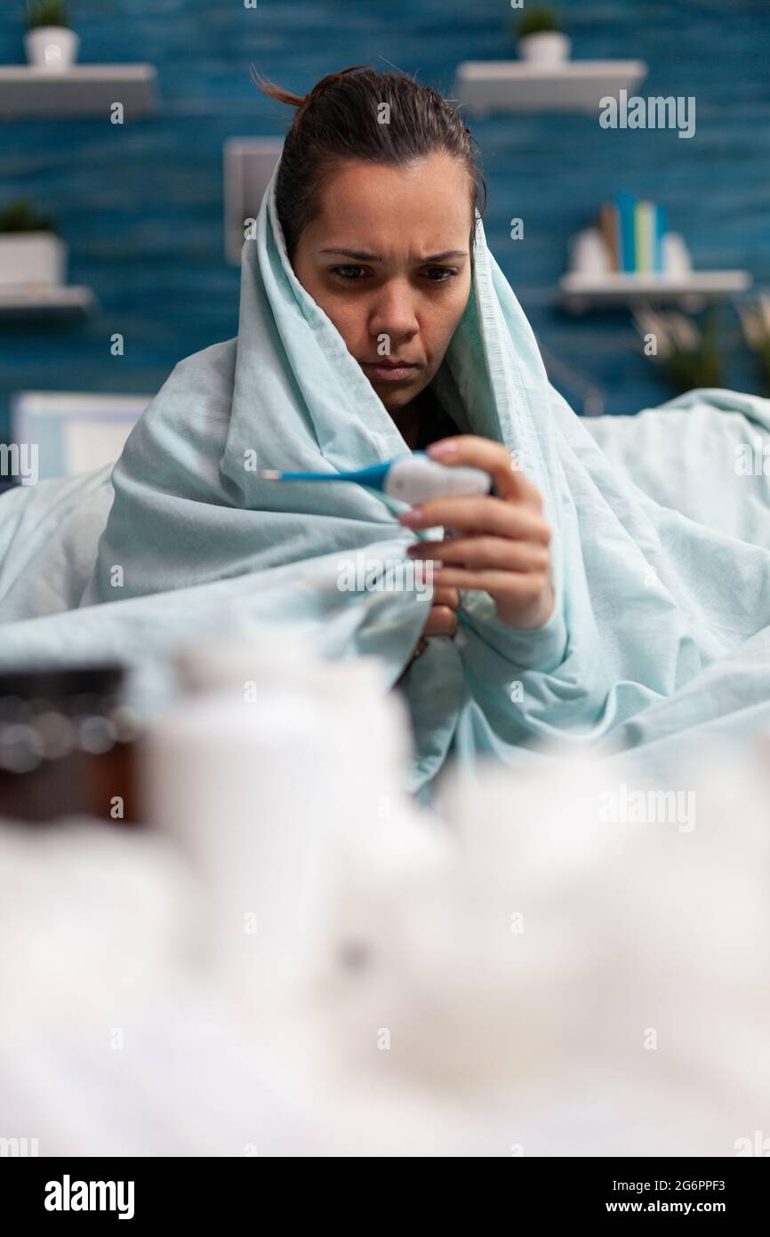 Sick woman measuring temperature with thermometer at home feeling sick ...