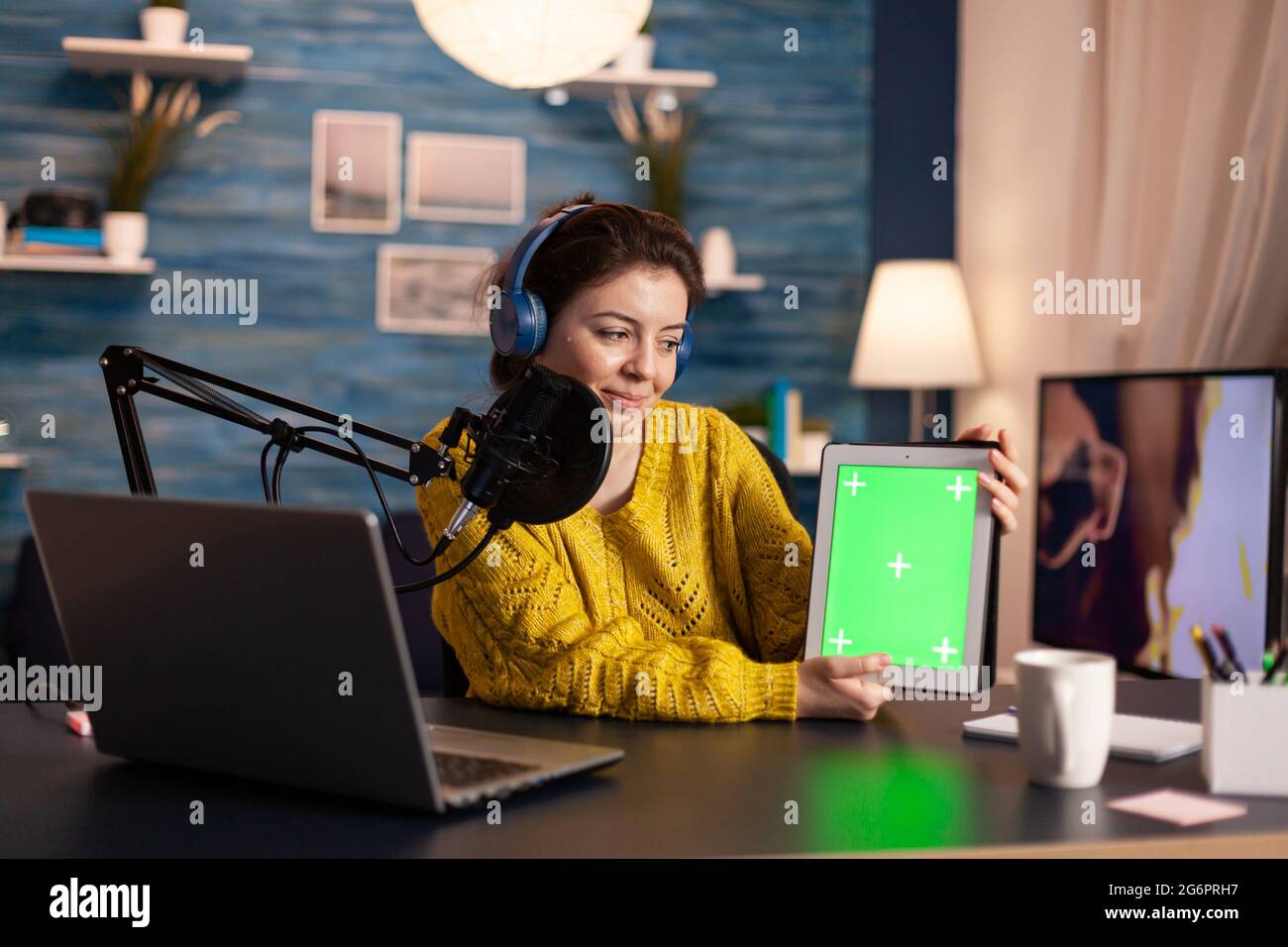 Blogger talking into microphone holding notepad with green screen ...