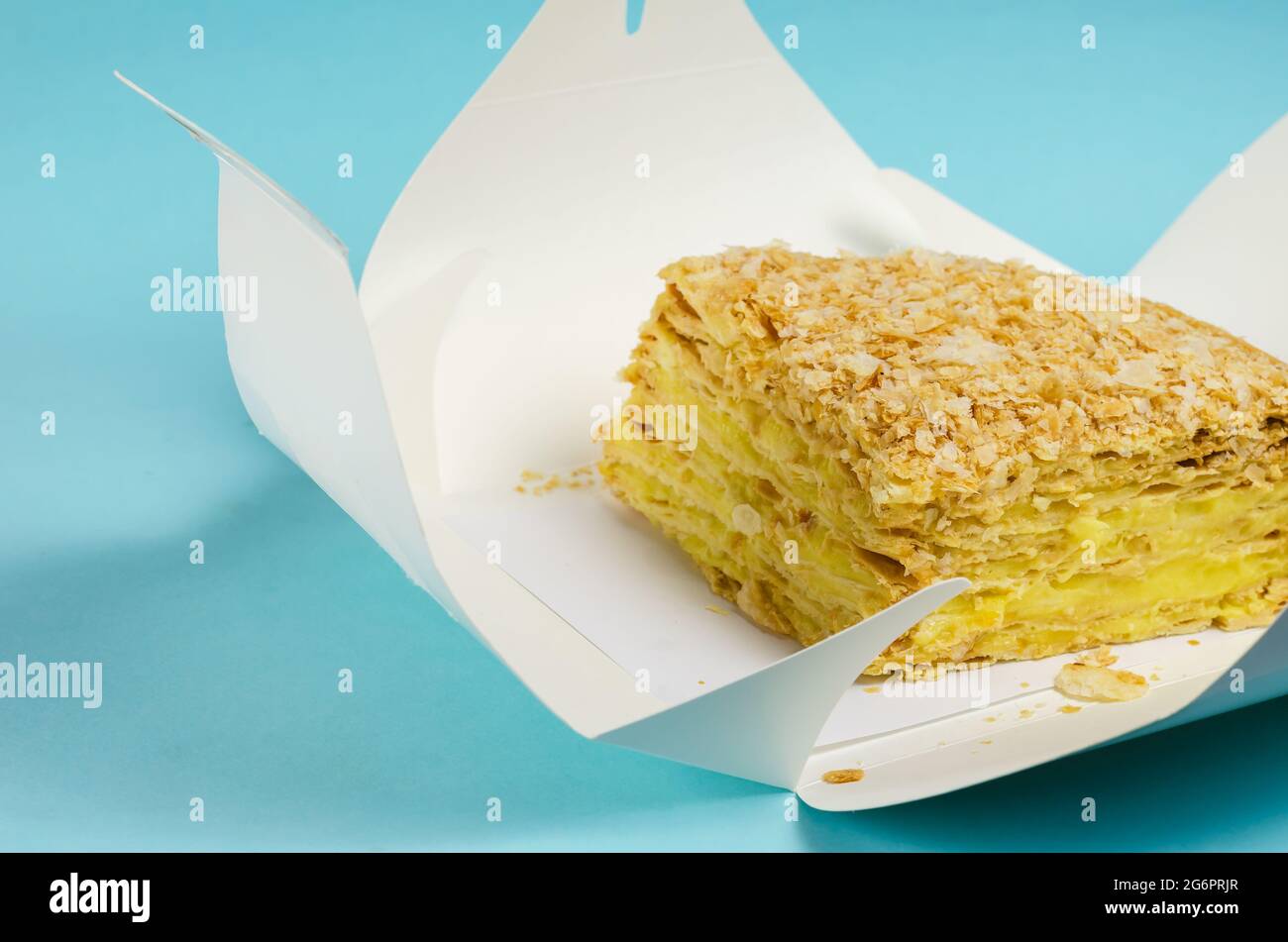 The cake is packaged in a white paper box on a light blue background ...