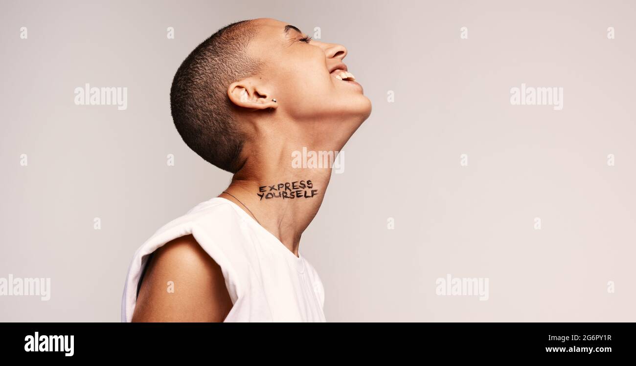 Cheerful androgynous woman with express yourself written on neck ...