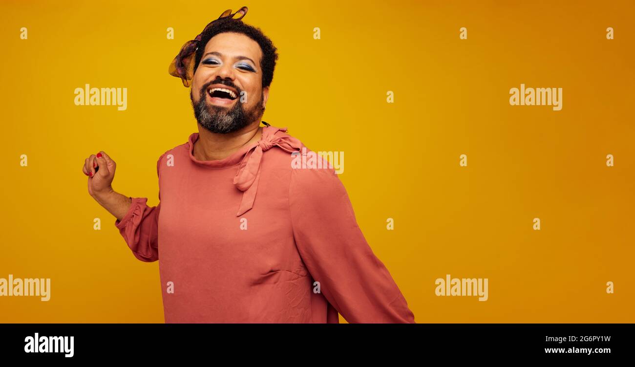Portrait of a genderqueer smiling on yellow background with copy space ...