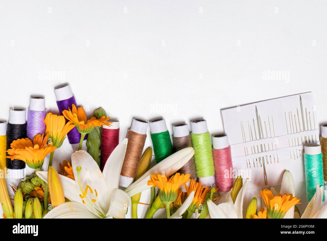 Multicolored threads and flowers on a white background with copy space ...