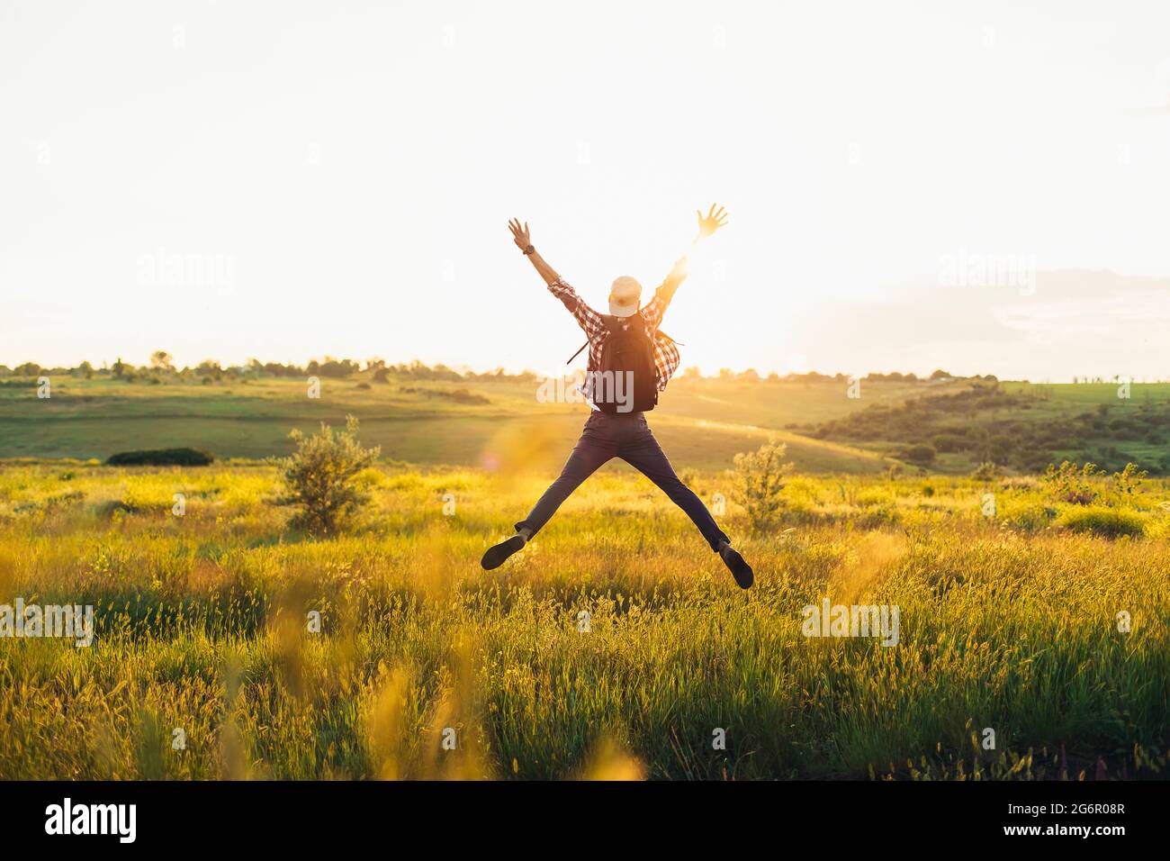 Rear view of man jumping up with outstretched arms, happy man with arms ...
