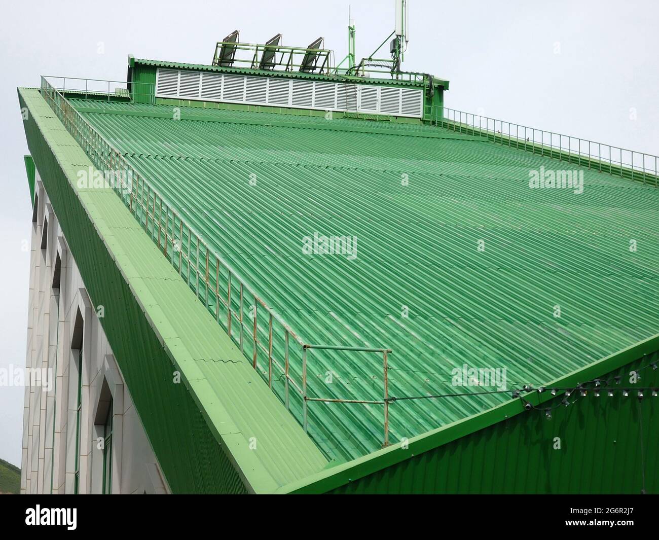 Sloping green roof of the building with a mobile communication antenna ...