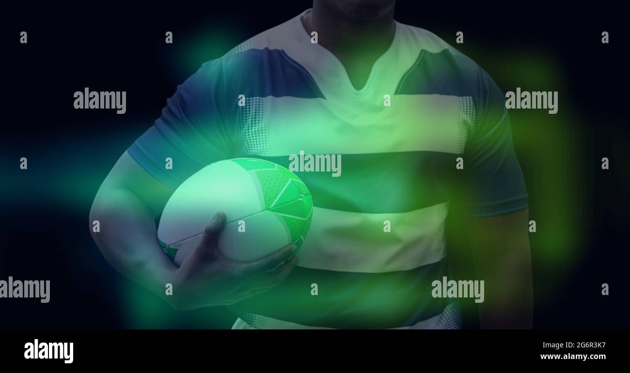 Composition of glowing green blur over male rugby player holding rugby ...