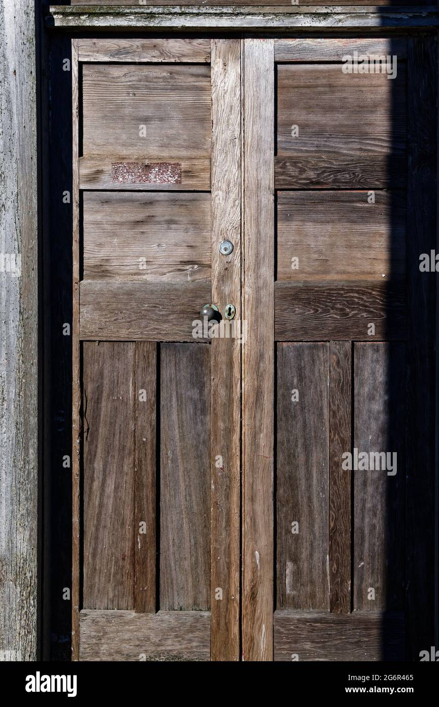 A heavy, wooden, panel door is glowing in the sun. It has a round ...