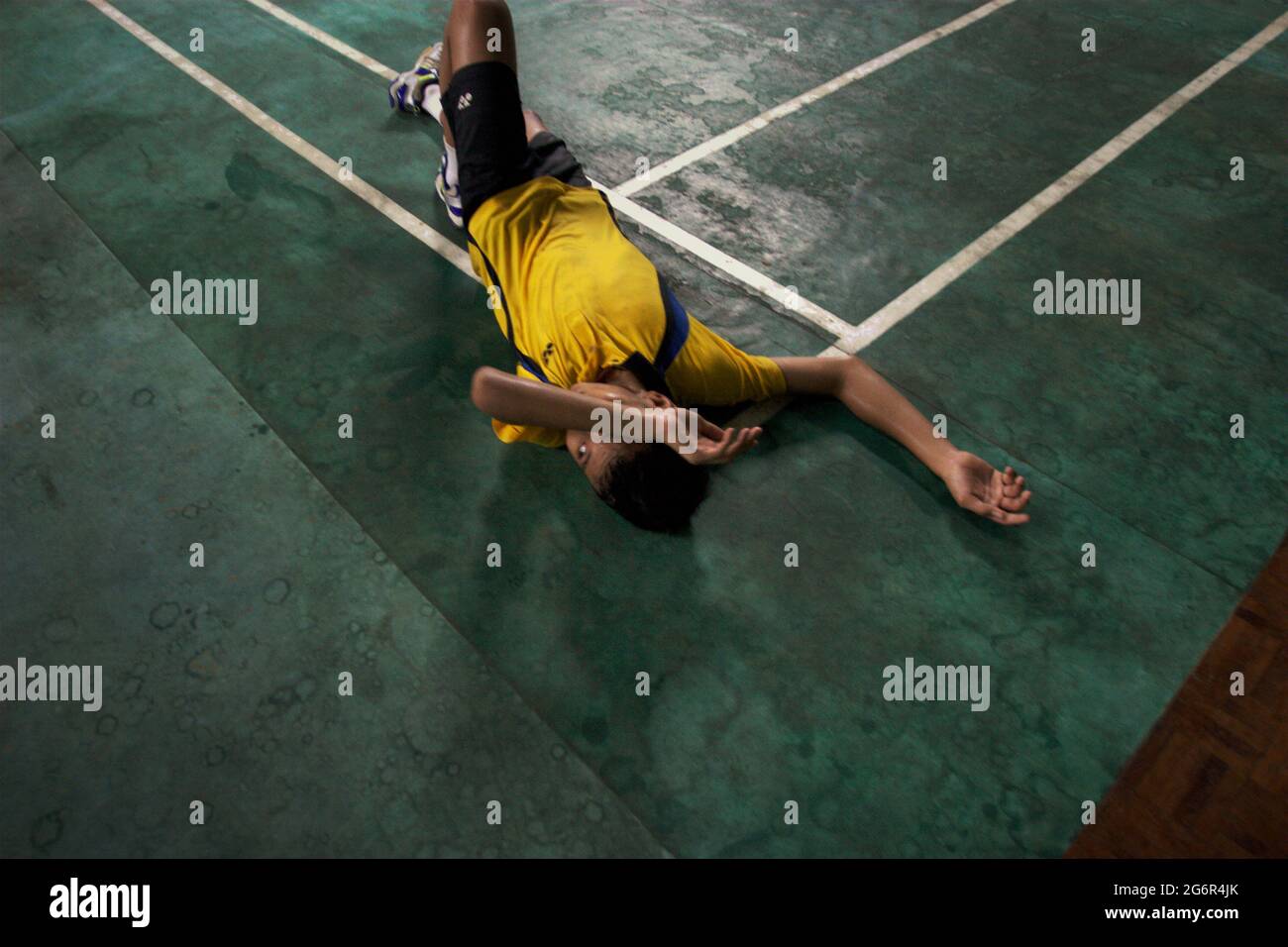 A young badminton athlete is resting on the floor after a training ...