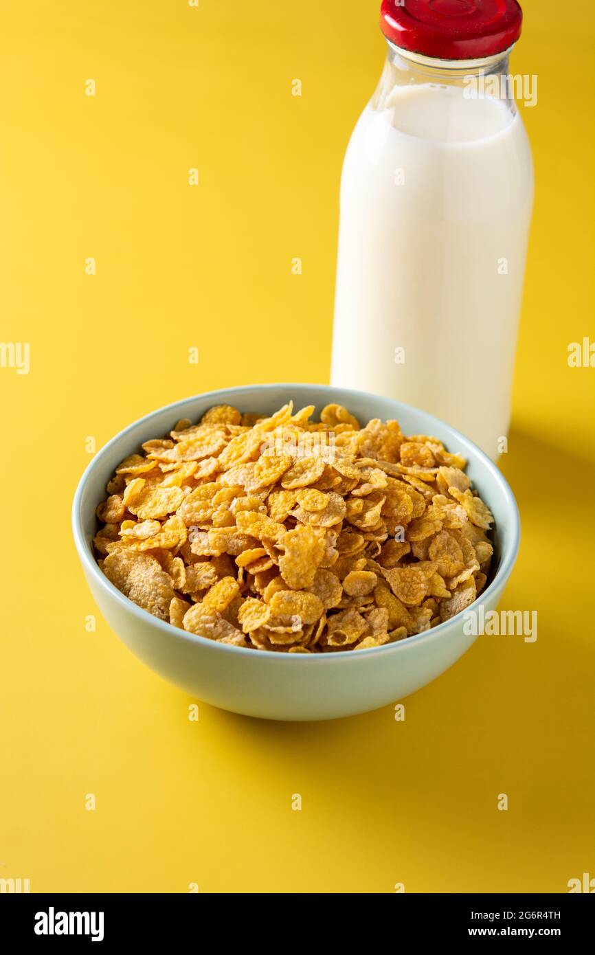Corn flakes in a blue bowl and milk bottle on yellow background Stock ...