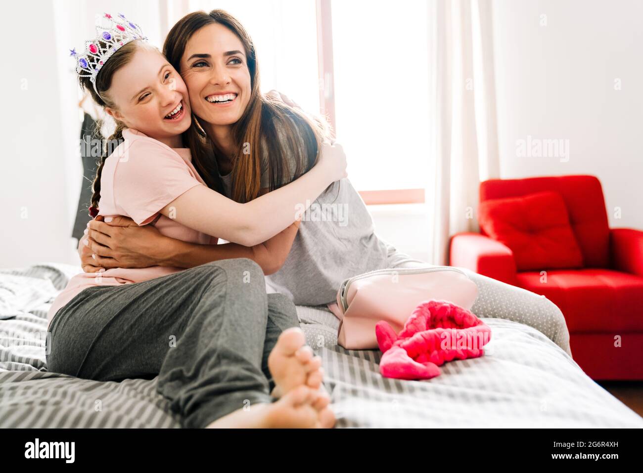 Woman and her daughter with down syndrome hugging while sitting on bad ...