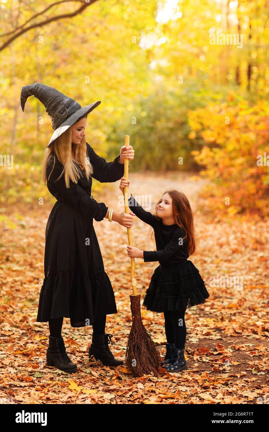 Full body woman and girl in witch costumes sweeping withered leaves ...