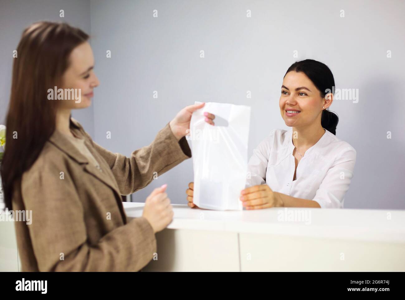 Female client taking bag with cosmetic supplies from friendly employee ...