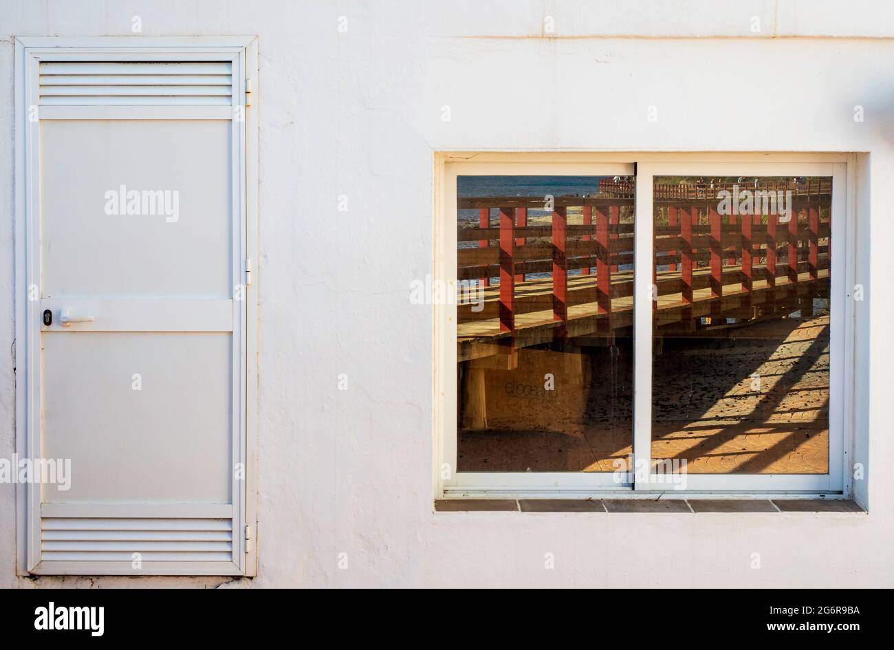 Closed door next to a window with the reflection of a wooden walkway ...
