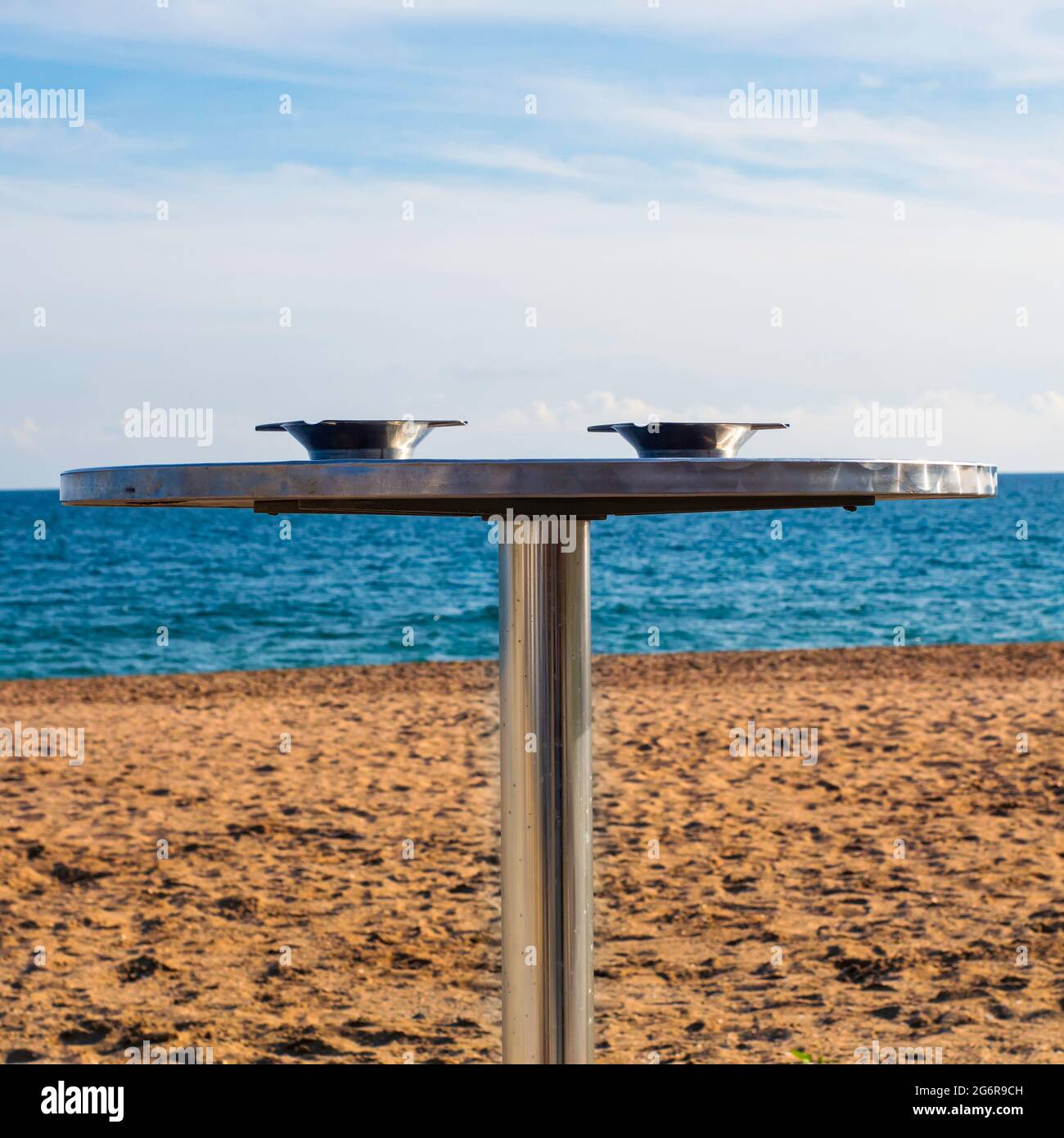 Two ashtrays on a metal table in front of the sea Stock Photo - Alamy