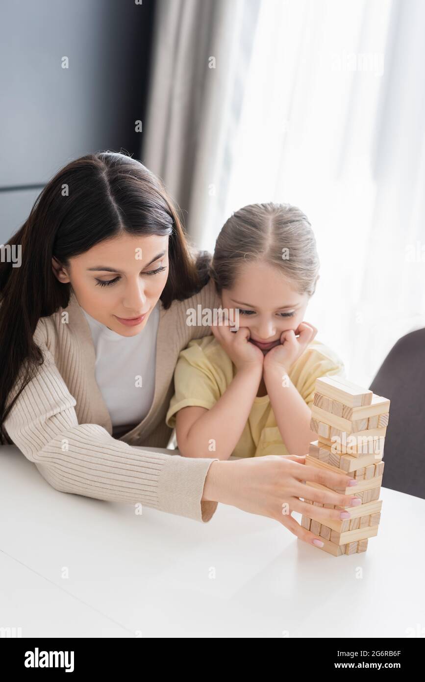 mother showing how to play wood blocks game to daughter at home Stock ...
