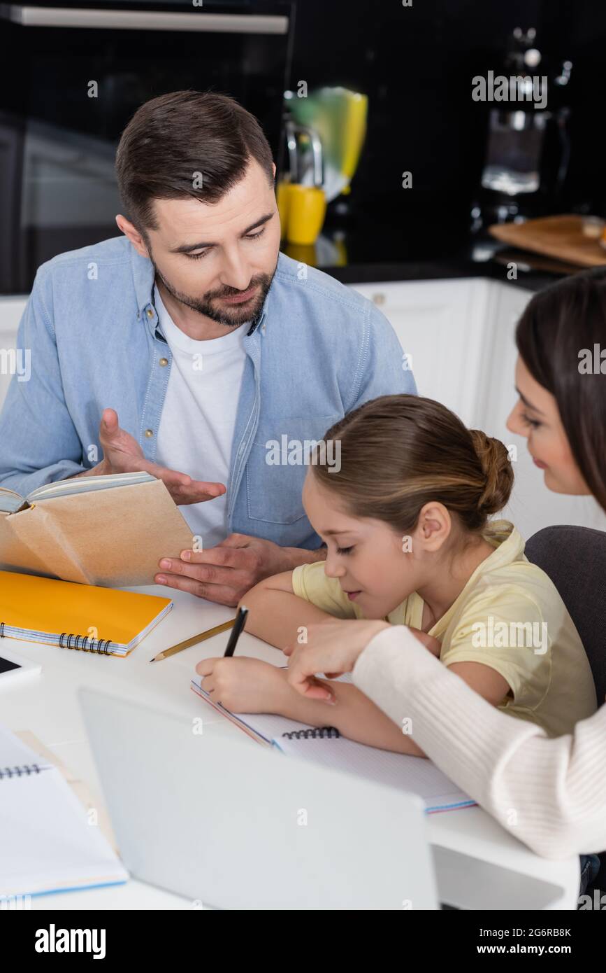 parents pointing at notebook near daughter doing homework Stock Photo ...