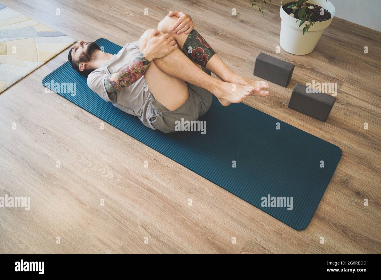 Young man starting the day with Wind-Relieving Pose at home Stock Photo ...