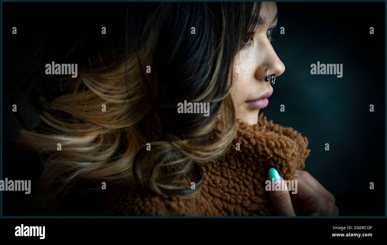 Side view of a young contented, trendy woman. She is posing for the ...