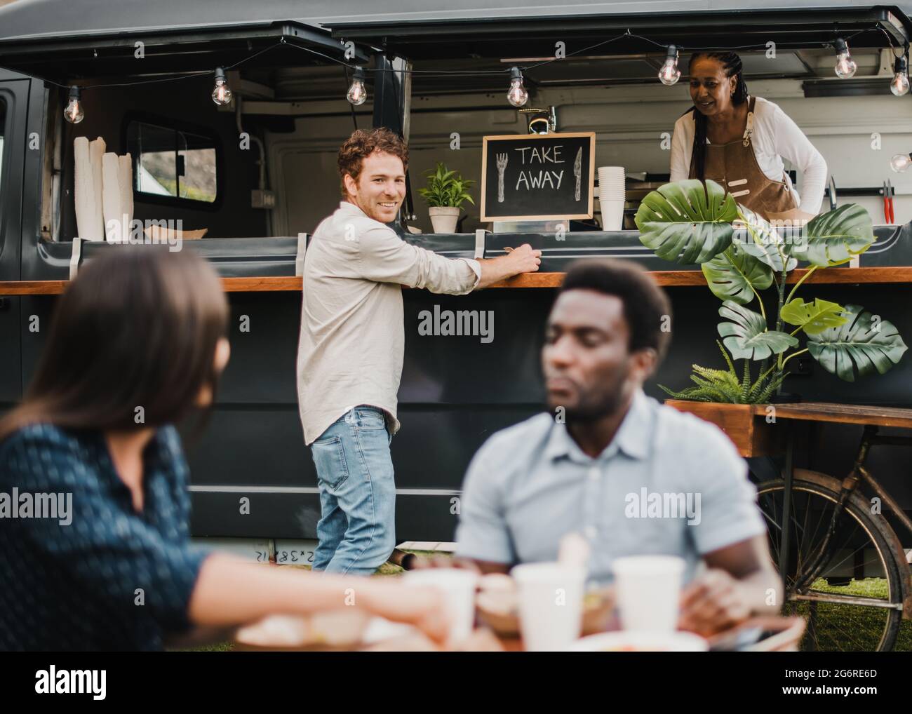 Multiracial people eating at food truck outdoor - Focus on center man ...