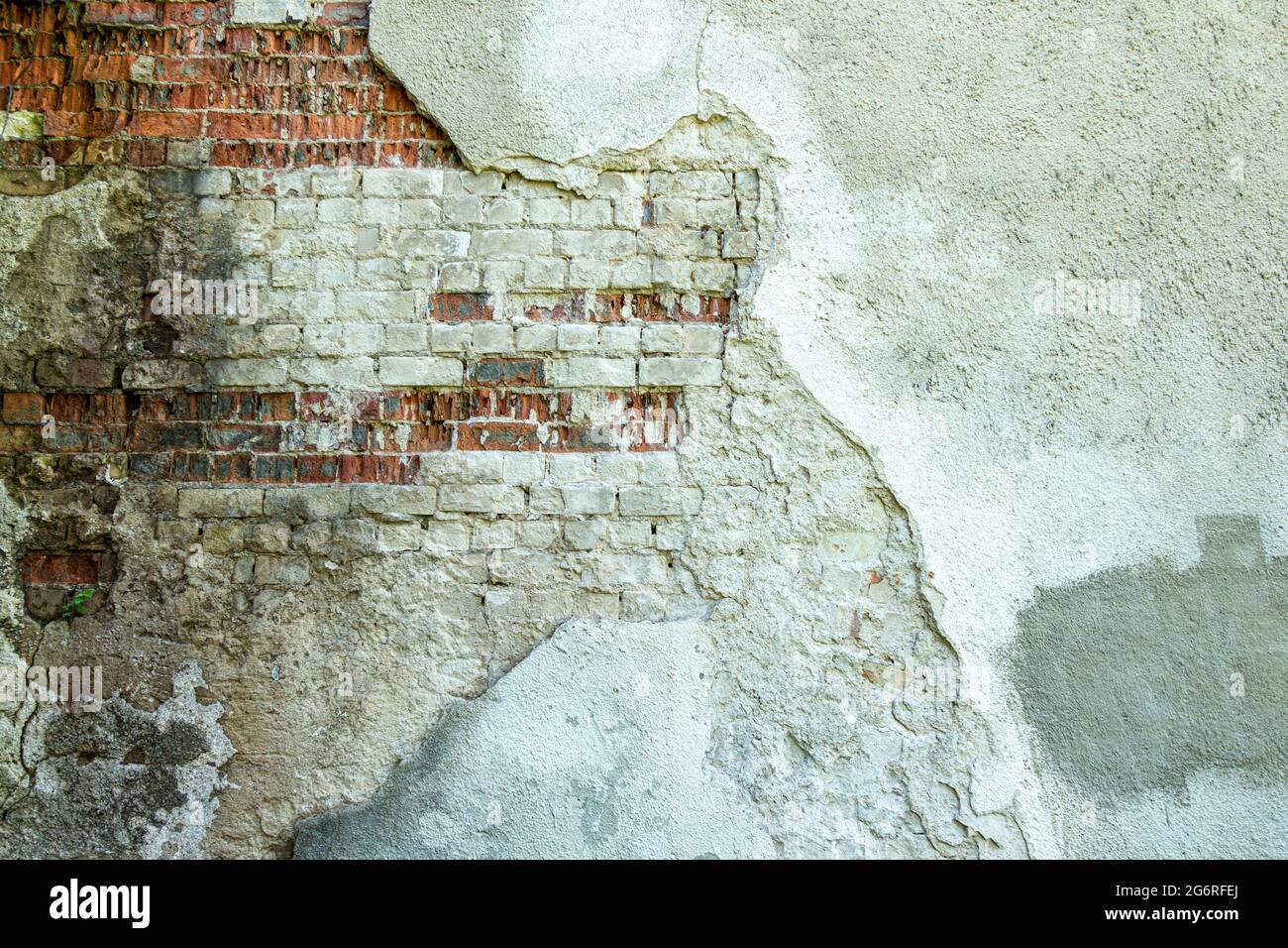 Gray plastered old brickwall with chipped stucco pieces. Grunge red and ...