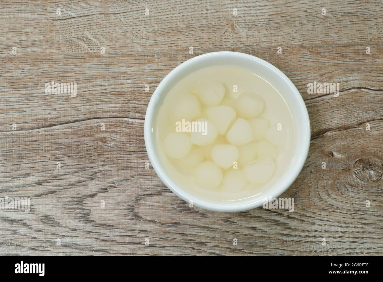 pickled single garlic with salt water in cup on table Stock Photo - Alamy