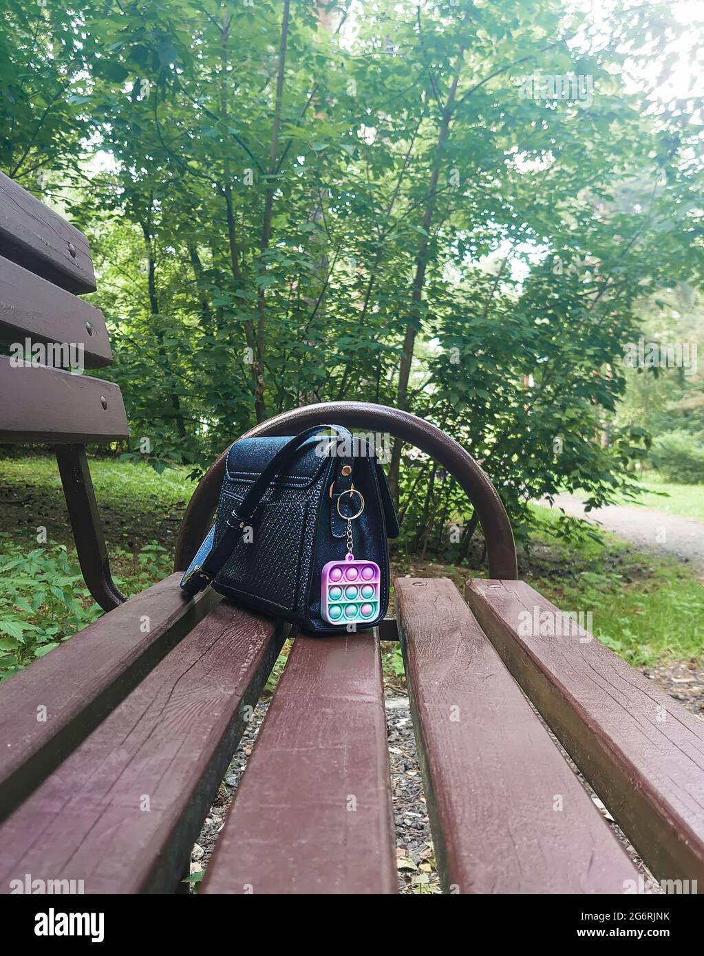 Antistress toy keychain hanging on a blue bag, on a park bench ...