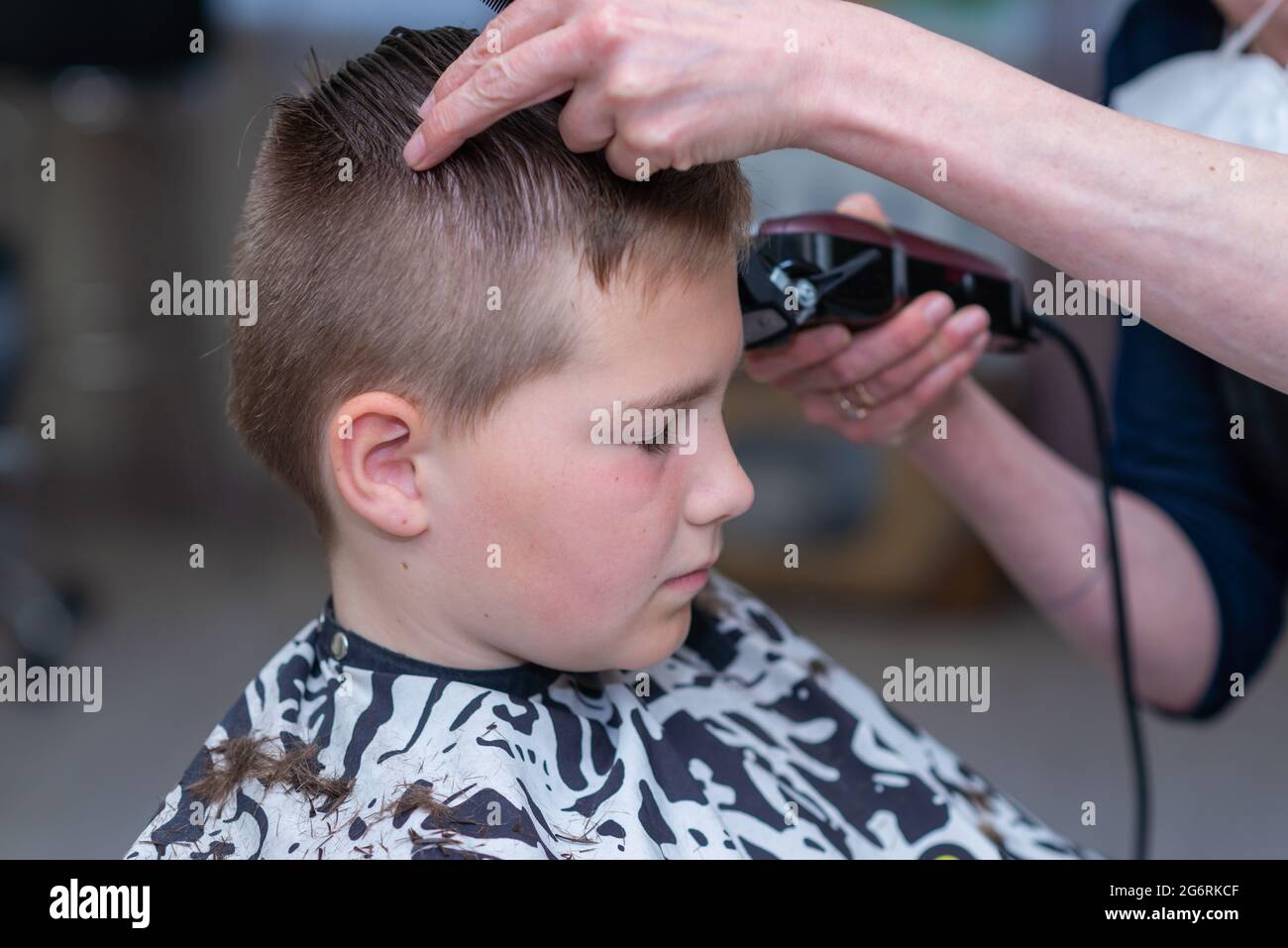 Cute kid boy have hair cut, professional barber doing haircut ...