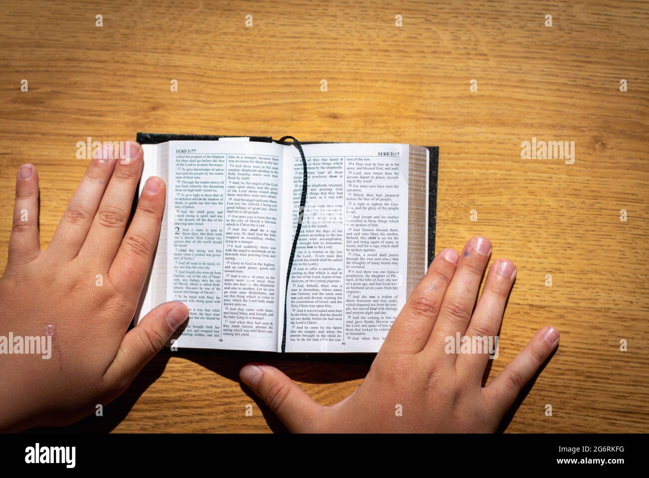 Childs hands hold a bible leaning on a wooden table. Small Book Holy ...