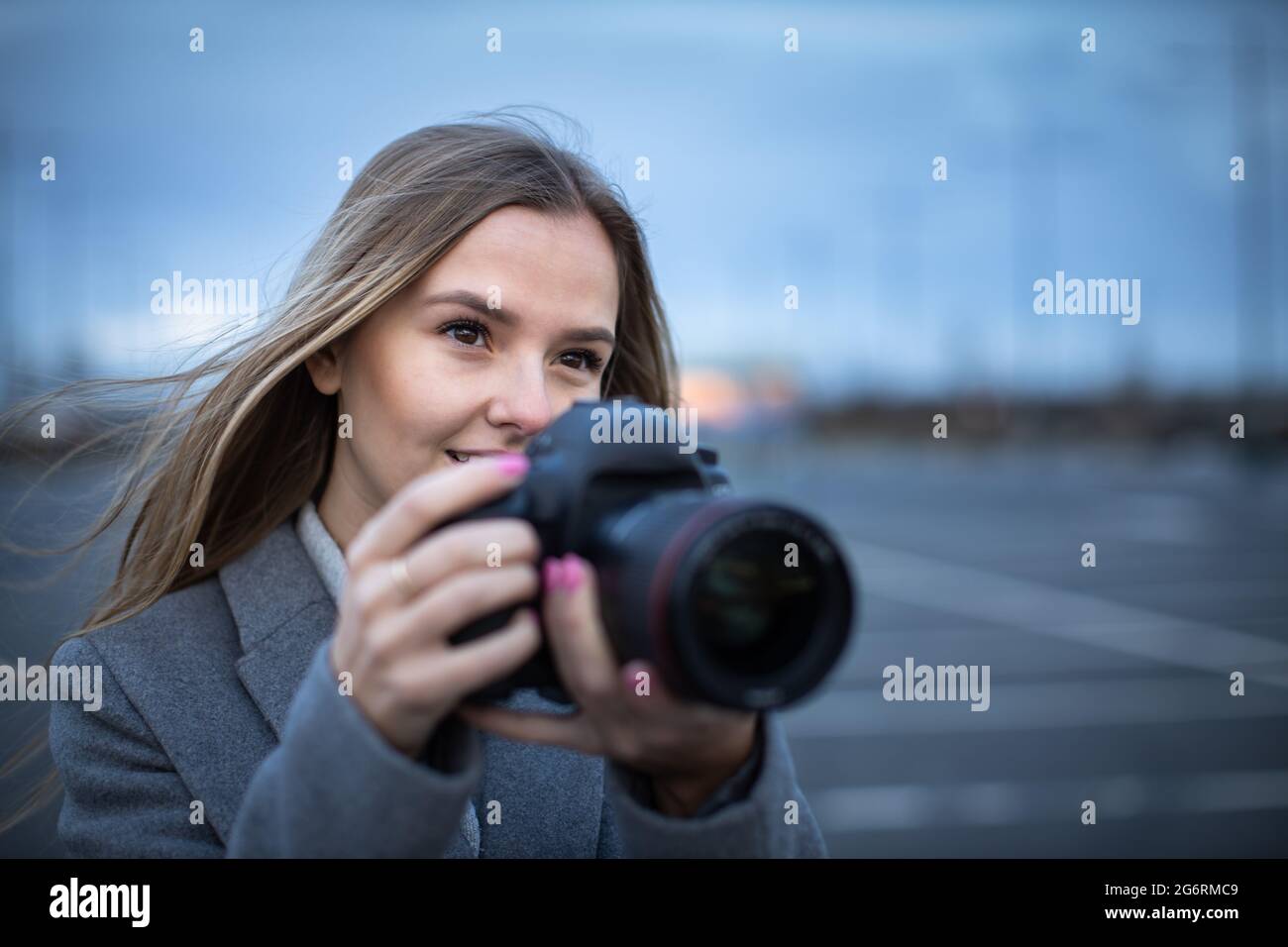 Pretty, young woman taking photos with her professional dslr camera ...