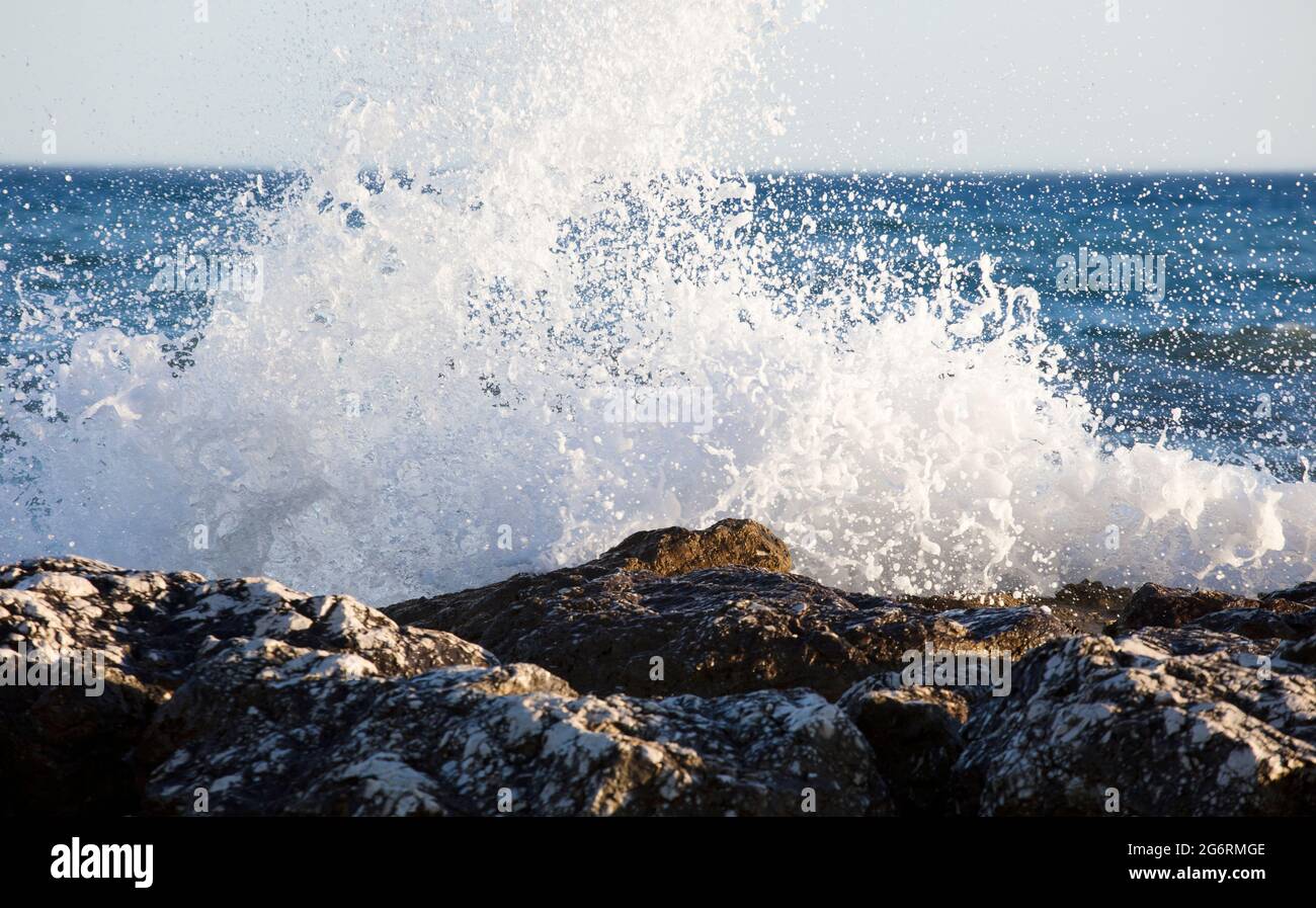 Waves splashed over rocks on a very windy day at sunset (golden hour ...