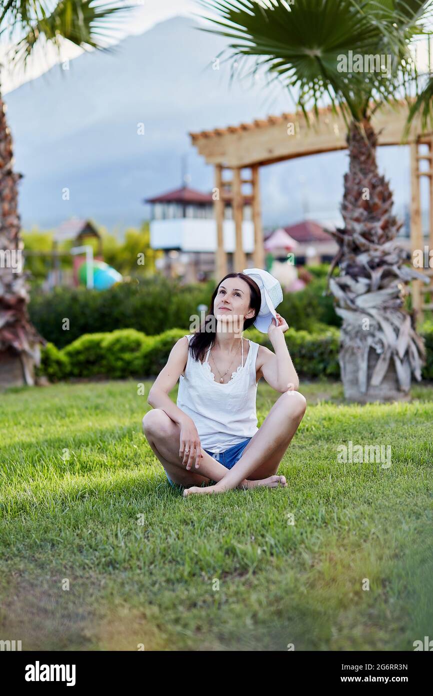A young girl sits on the lawn and practices breathing exercises ...