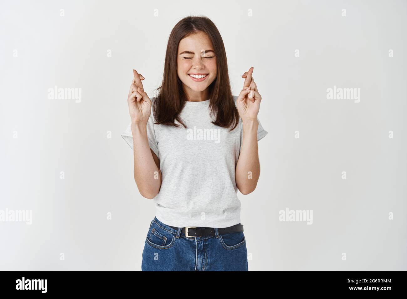 Enthusiastic, excited attractive woman in t-shirt, hold fingers crossed ...
