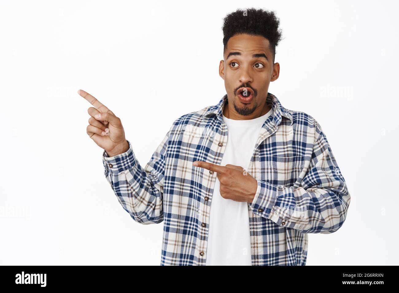 Portrait of surprised young Black guy pointing, looking left in awe ...