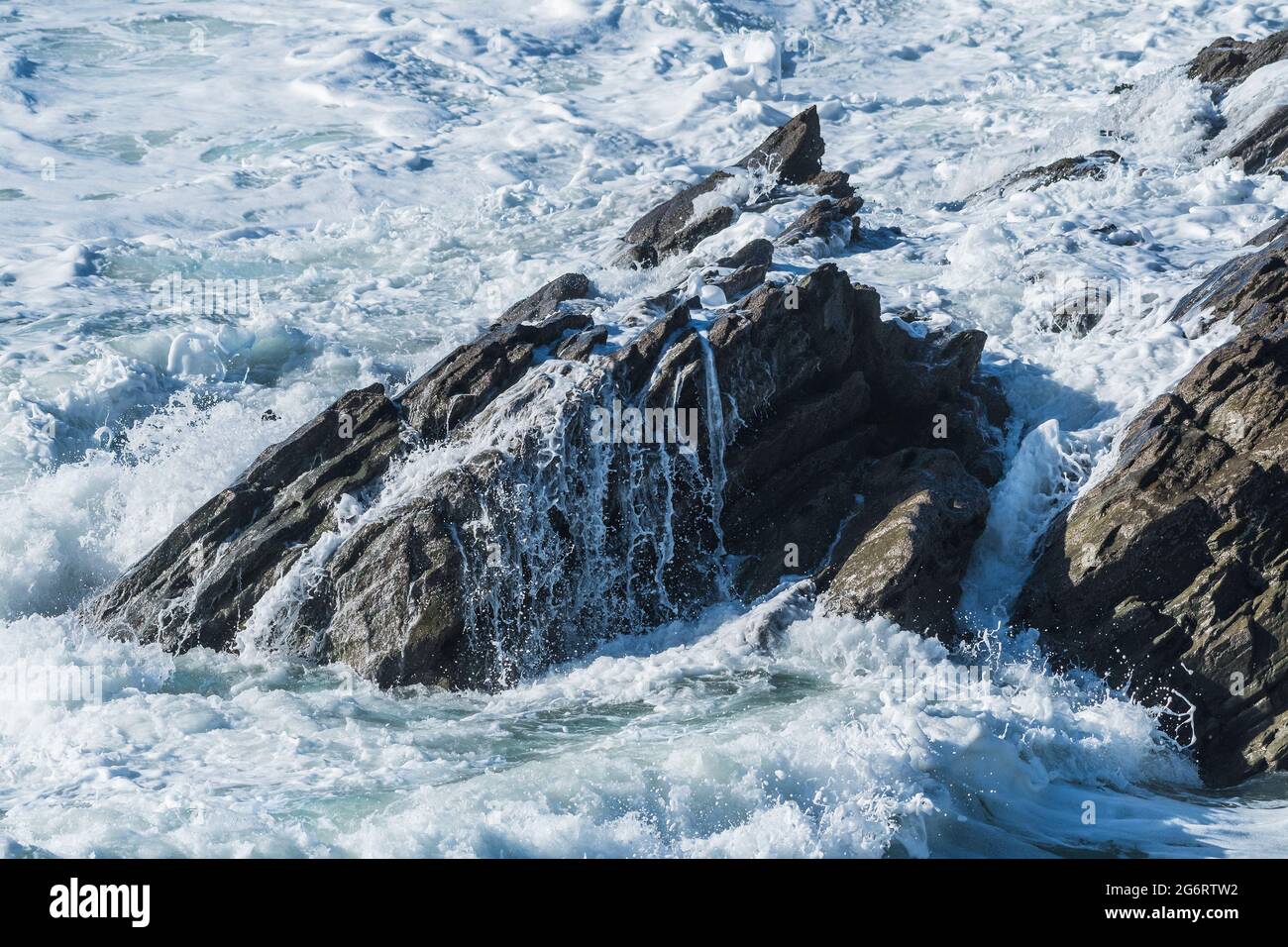 Seawater flowing over a rock on the coast at Towan Head in Newquay in ...