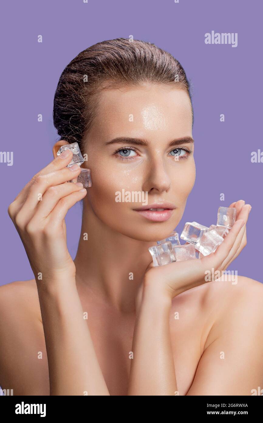 Beautiful woman with natural looking makeup holding ice cubes near face ...