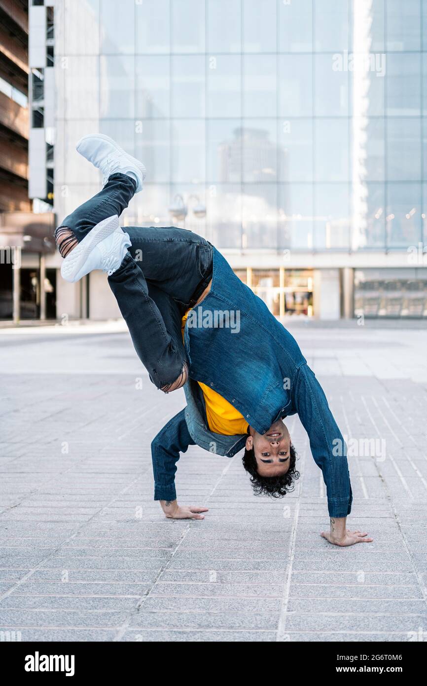 Talented young man dancing in the street and practicing break dance ...
