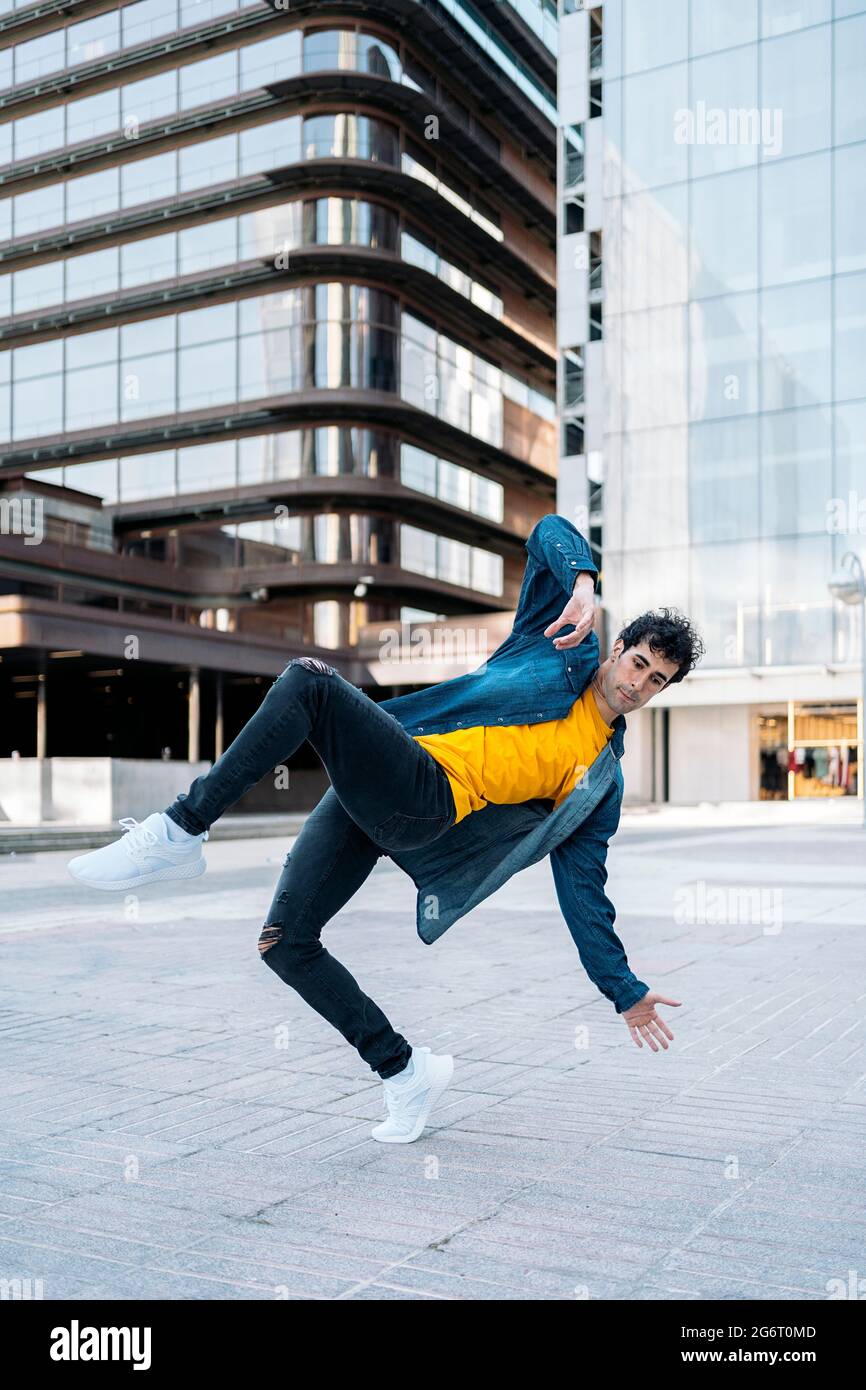 Talented young man dancing in the street and practicing break dance ...