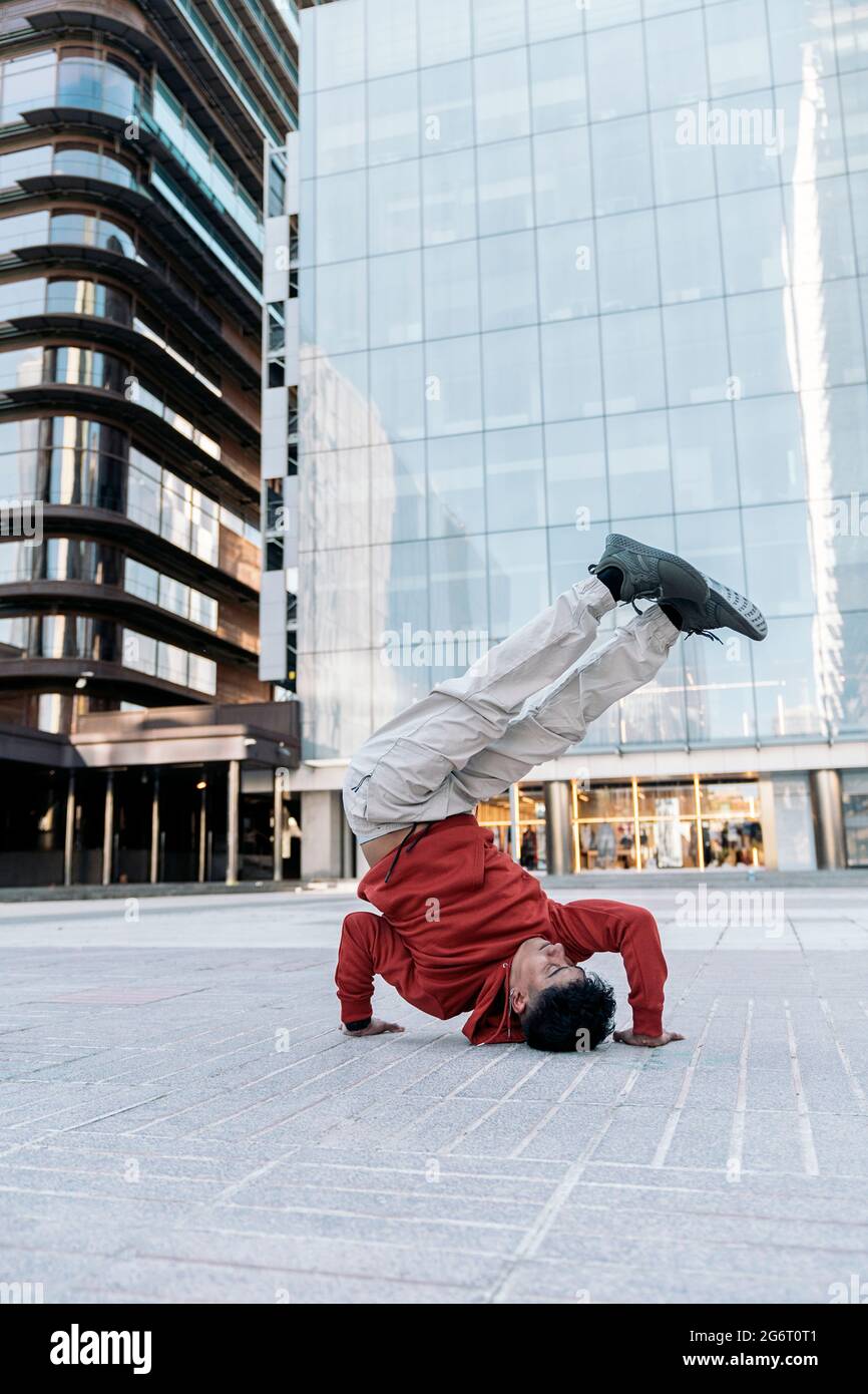 Talented boy practicing break dance in the street against big modern ...