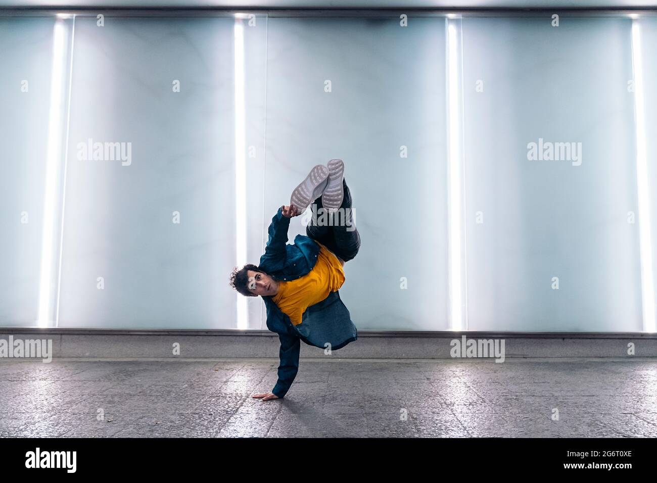 Talented young man dancing against white wall with lights and ...