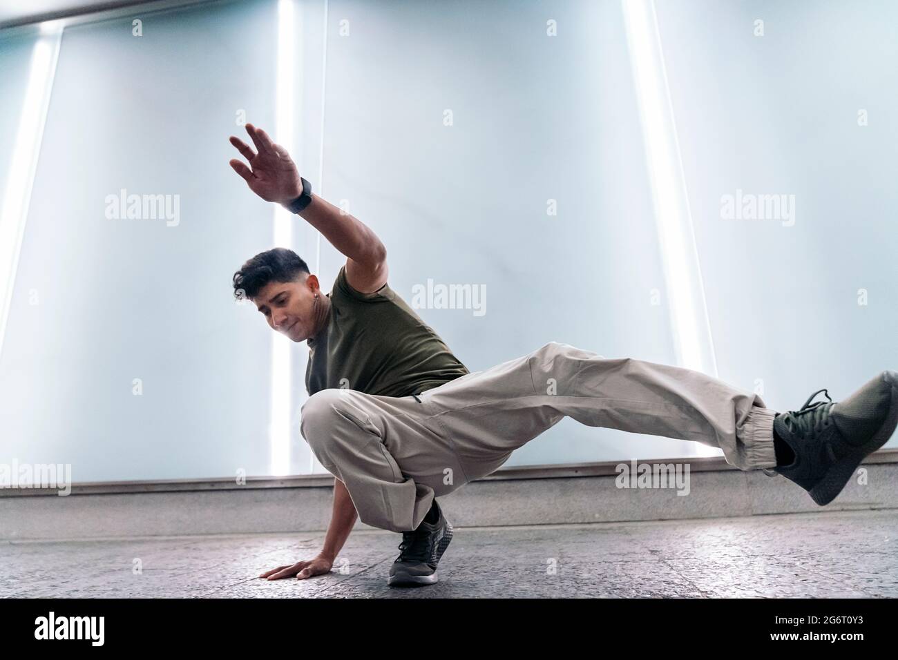 Talented boy practicing break dance against white wall with lights and ...