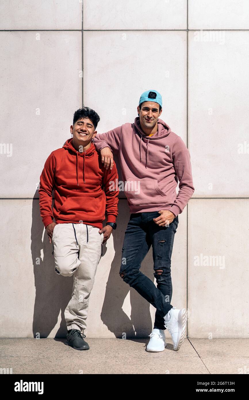 Happy and cool male friends smiling and looking at camera against white ...