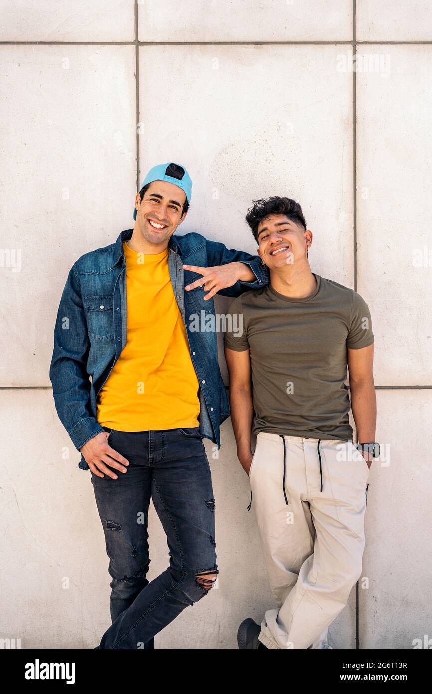 Happy and cool male friends smiling and looking at camera against white ...