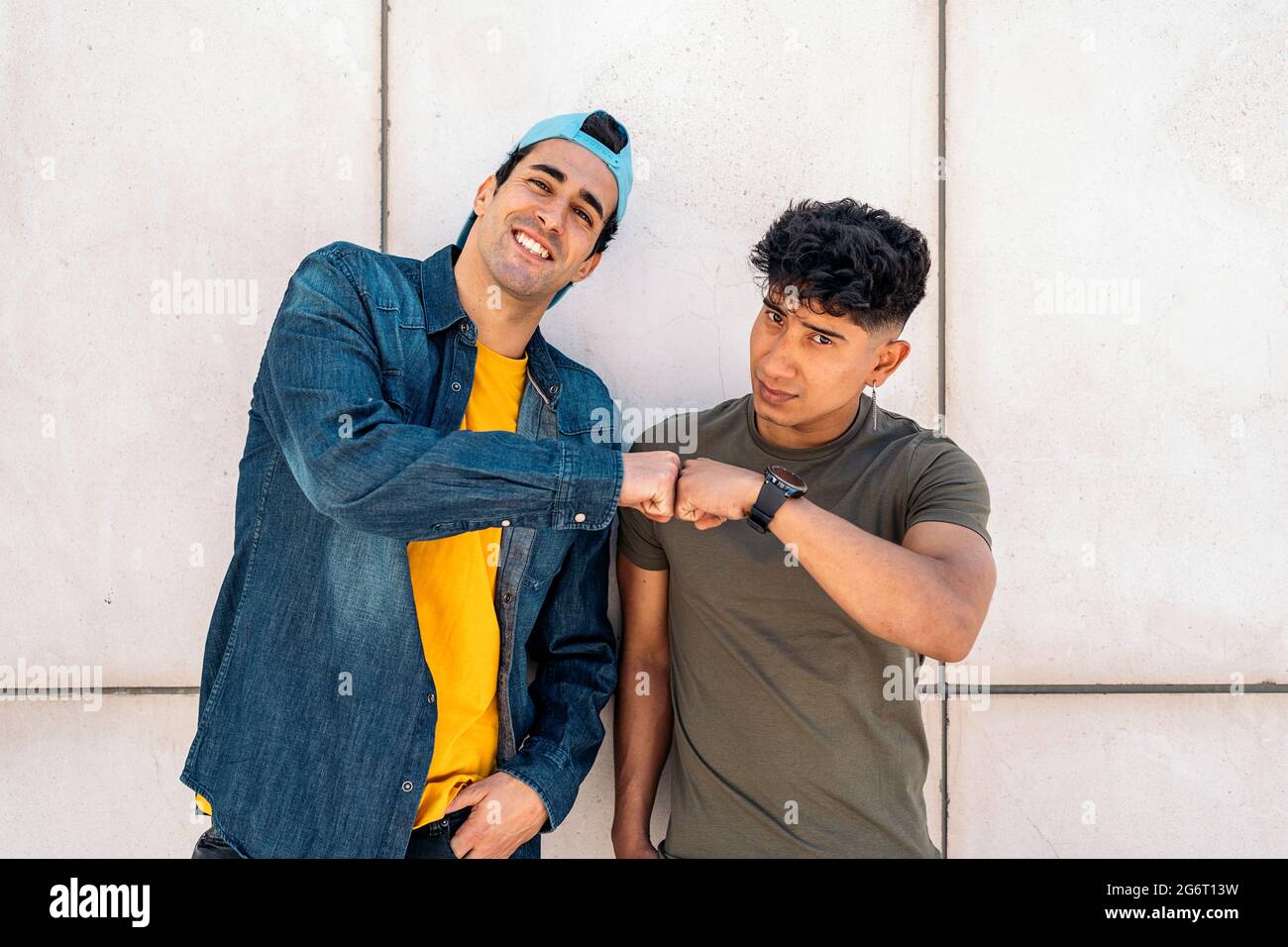Happy and cool male friends smiling and looking at camera against white ...